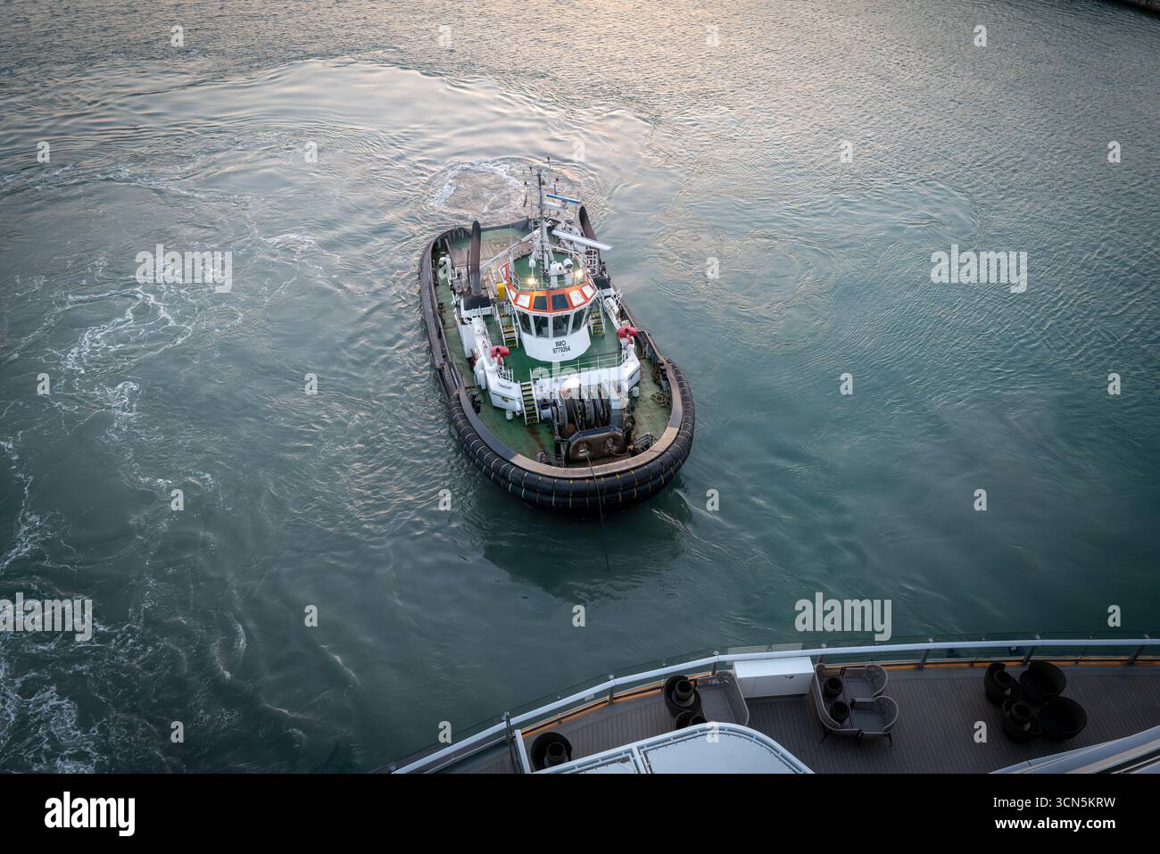 Close-up of a tugboat maneuvering in the harbor waters, assisting a ...