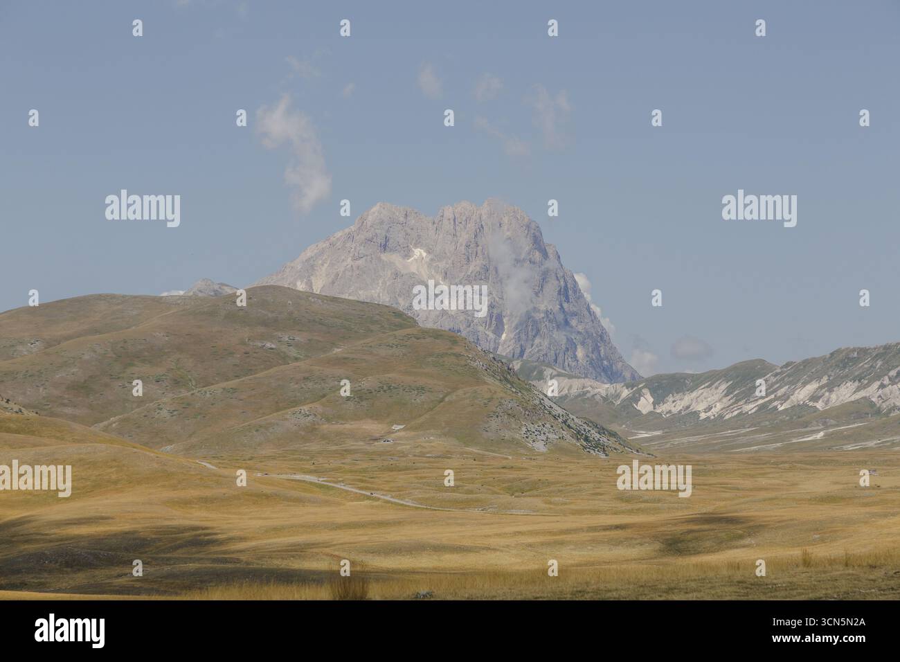 View of rolling golden grasslands meet the majestic, snow-touched Gran ...