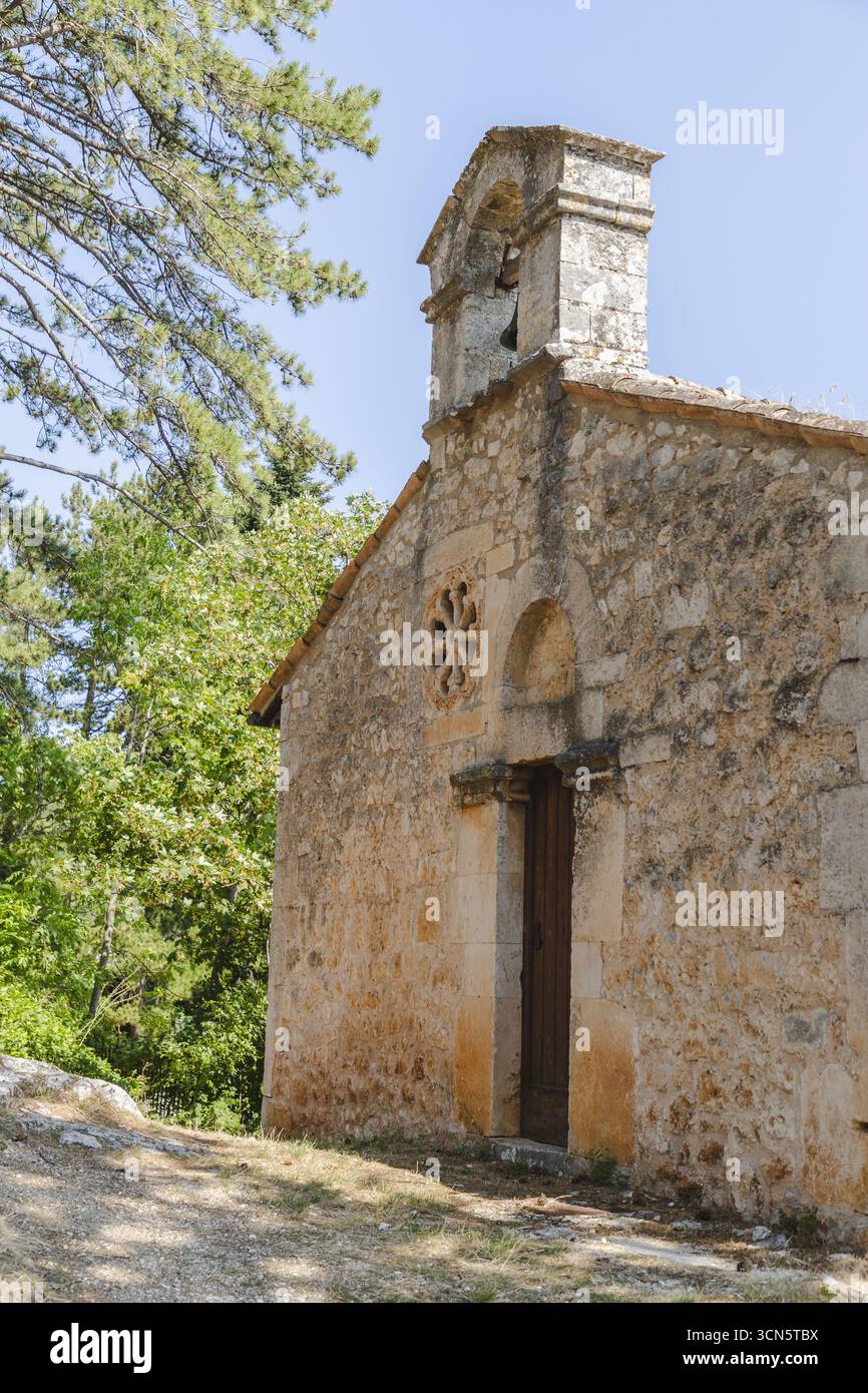 View of the rustic stone chapel stands bathed in sunlight, its simple ...