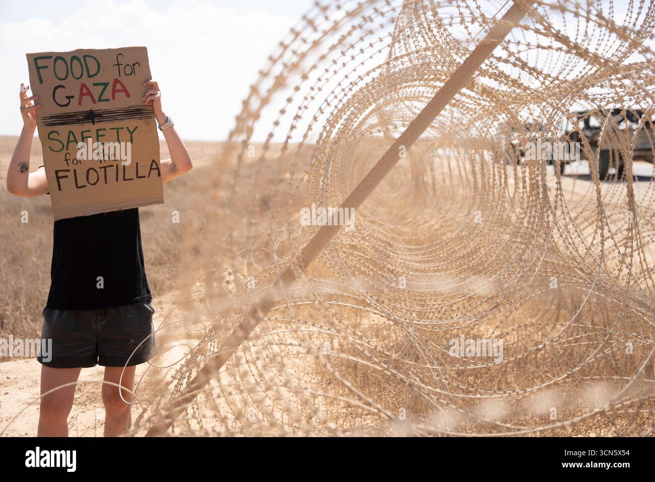 An activist holds up a sign near razor wires during a protest against ...