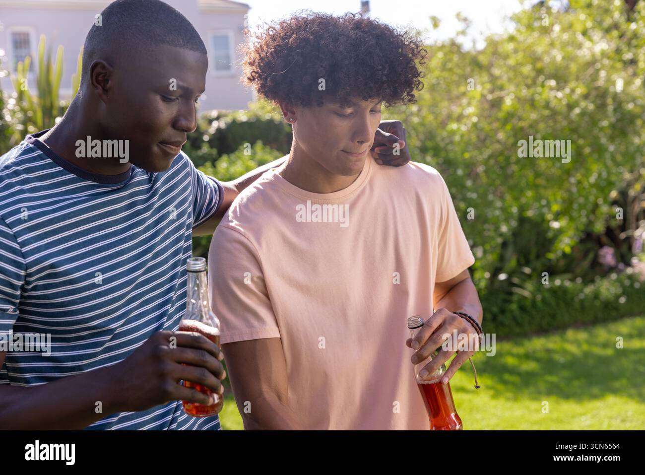 Diverse male friends standing together on grass lawn in backyard ...