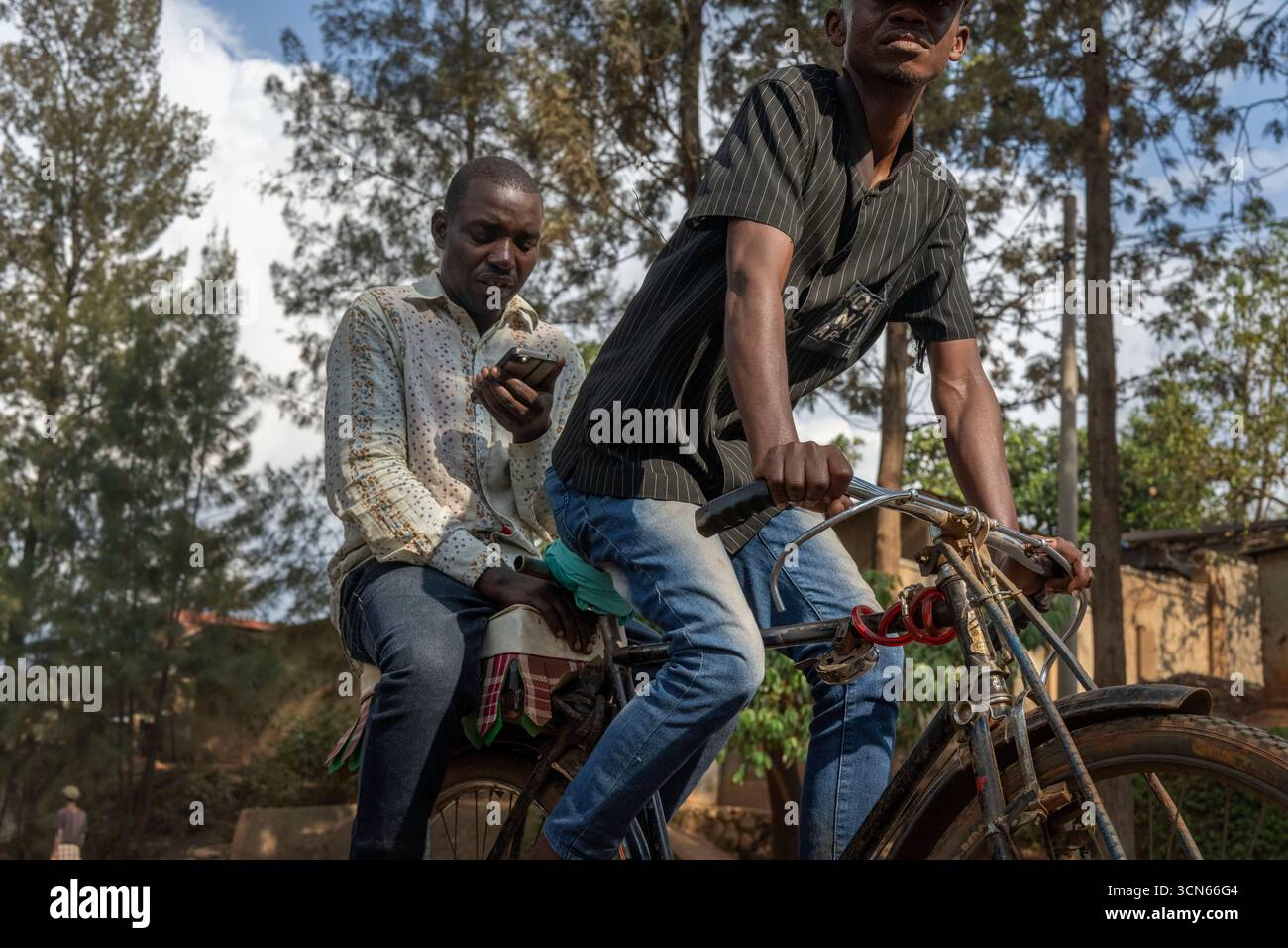A man checks his phone as he rides on a velo-taxi in Kigali, Rwanda ...