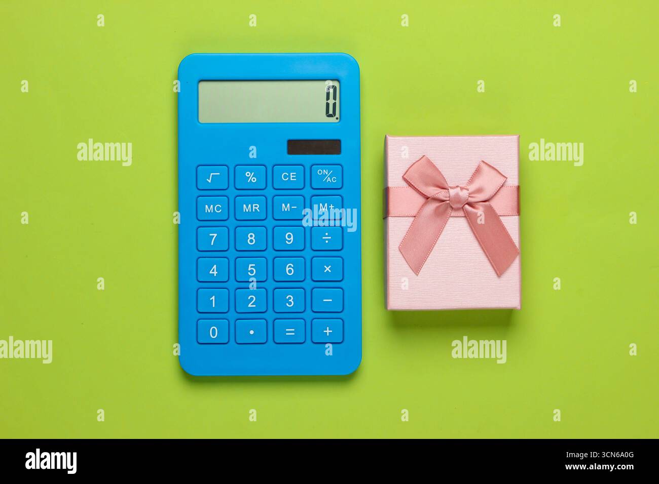 Calculator and gift box with bow on green background. Calculation of ...