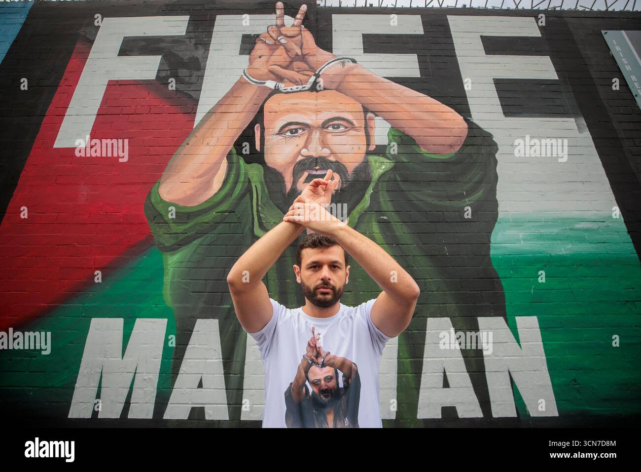 Aarab Barghouti poses in front of an image of his father, Marwan ...