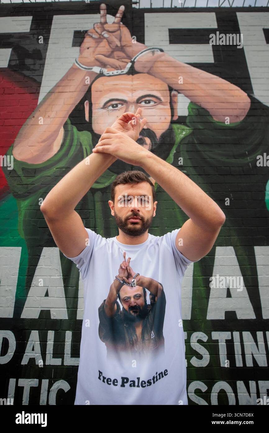 Aarab Barghouti poses in front of an image of his father, Marwan ...