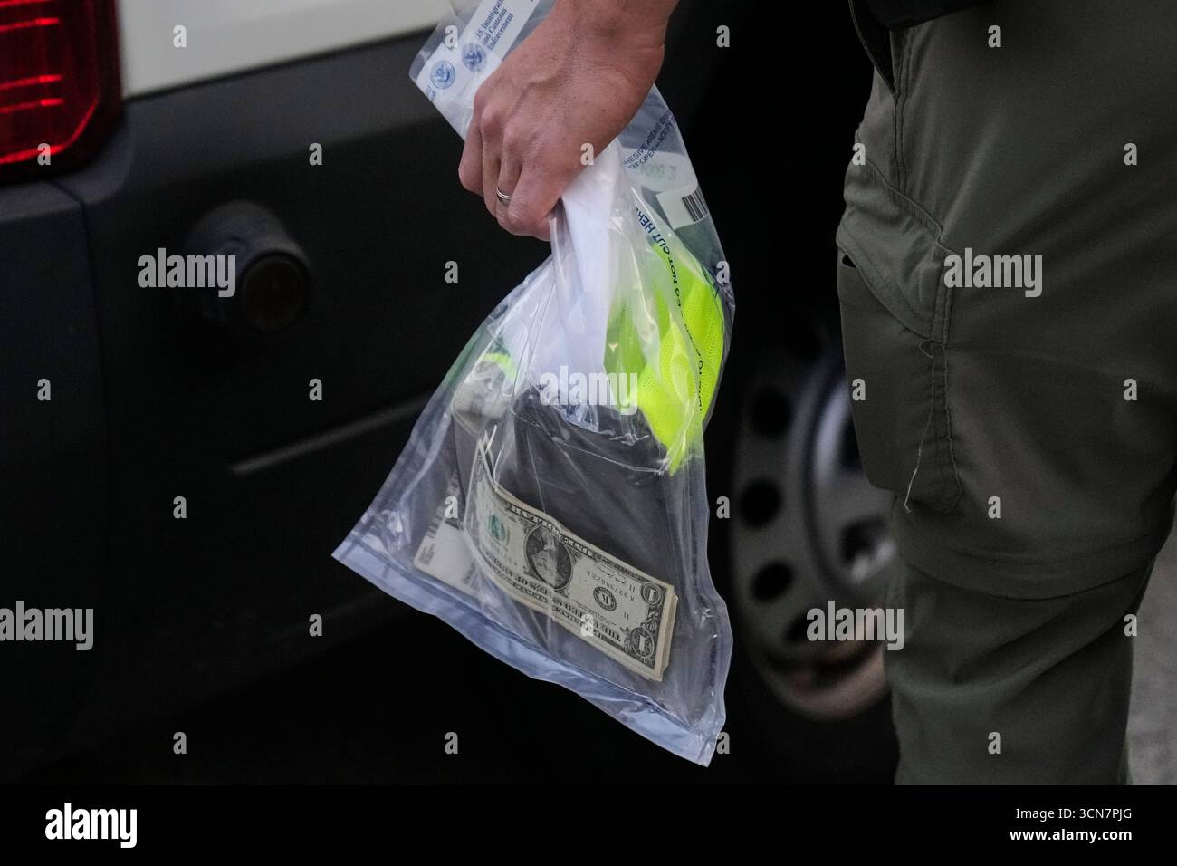 U.S. Immigration and Customs Enforcement agents hold belongings ...