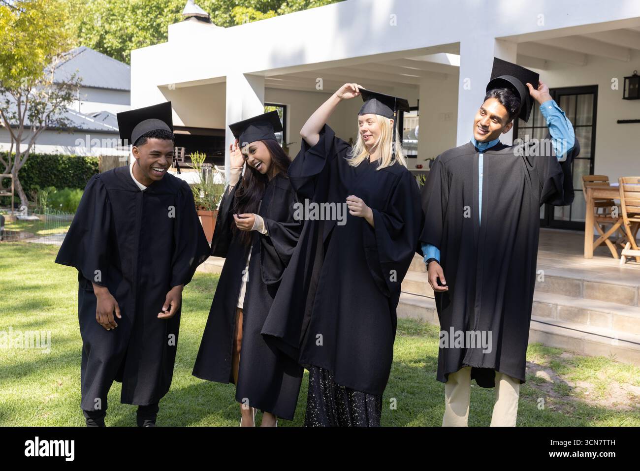 Diverse graduate friends adjusting caps hi-res stock photography and ...