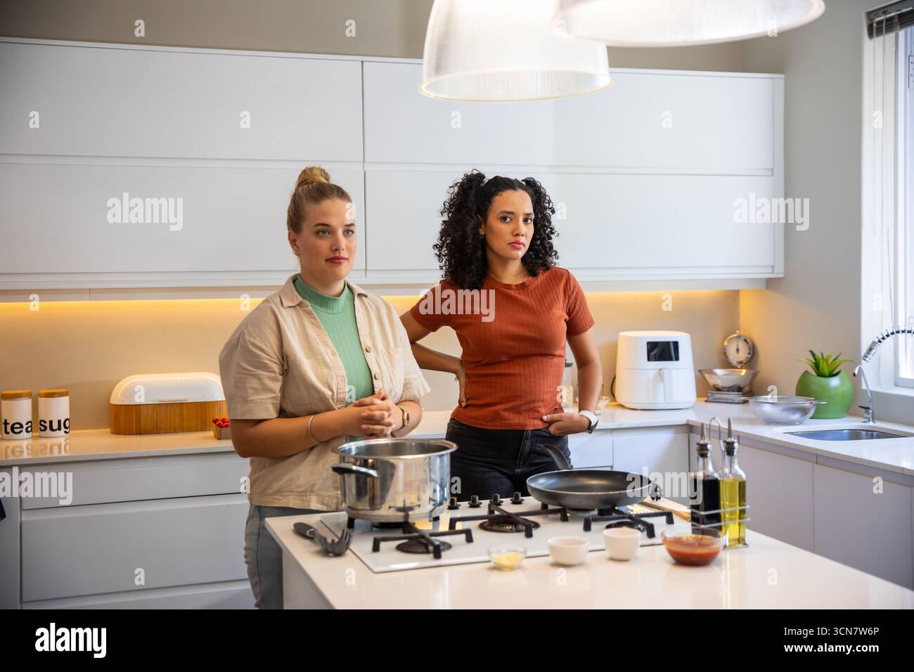 Diverse female friends chopping ingredients at kitchen island while ...