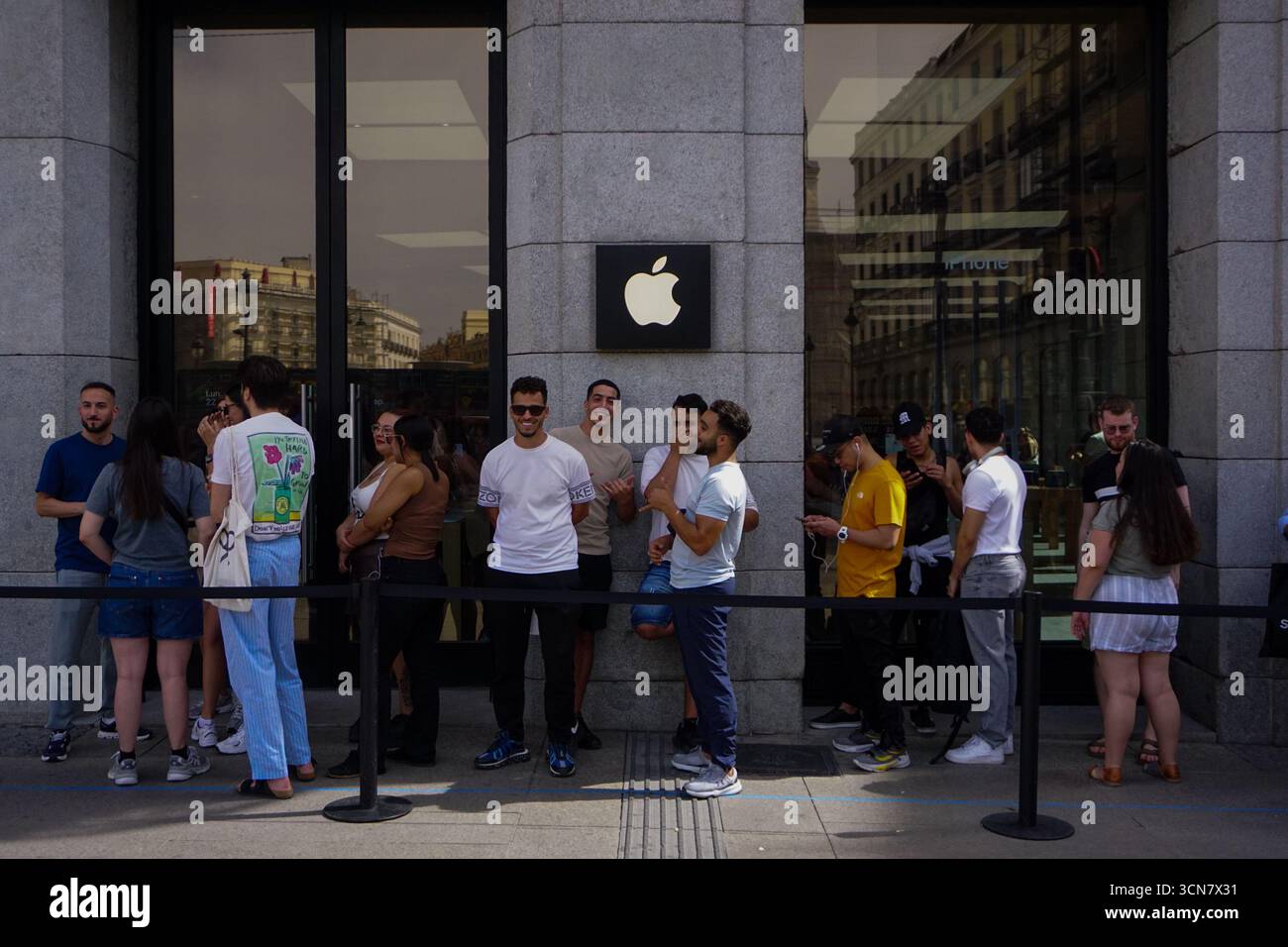 Apple customers wait in front of a company logo outside the Apple Store ...