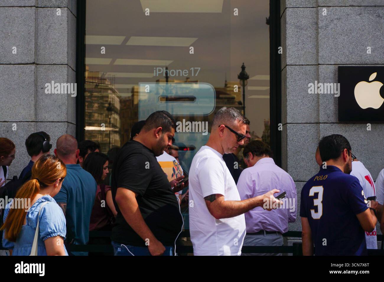 A man in a line checks his phone outside the Apple Store during the ...