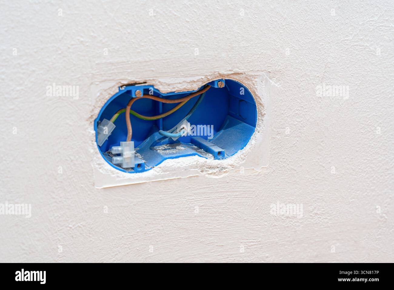 Close-up of a plastic electrical wall box with exposed wires and ...