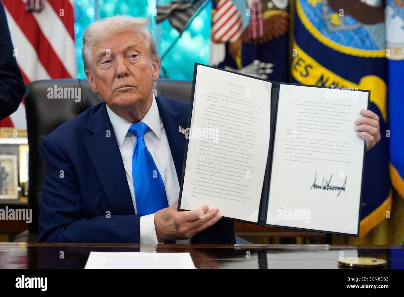 President Donald Trump holds up the signed Gold Card executive order in ...