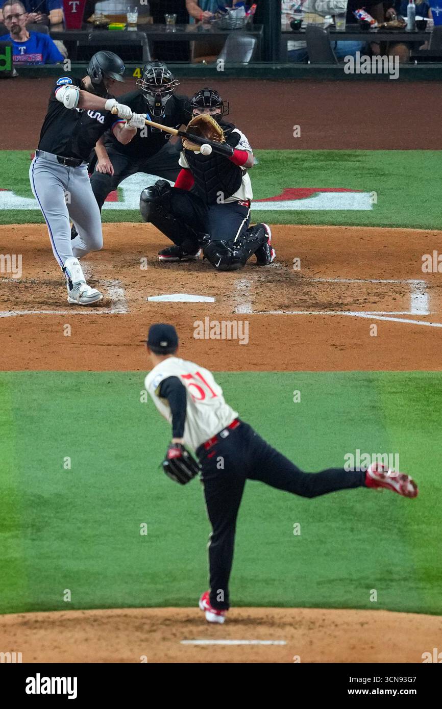 Miami Marlins' Graham Pauley, top, connects for a hit off Texas Rangers ...