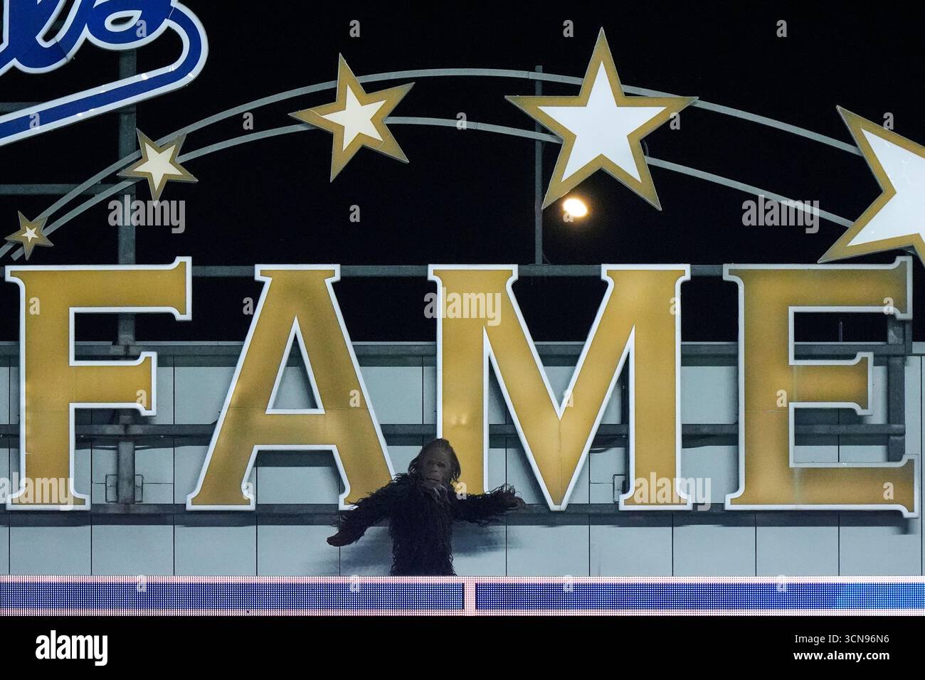 A man dressed as Pasquatch walks on a roof in the outfield to celebrate ...