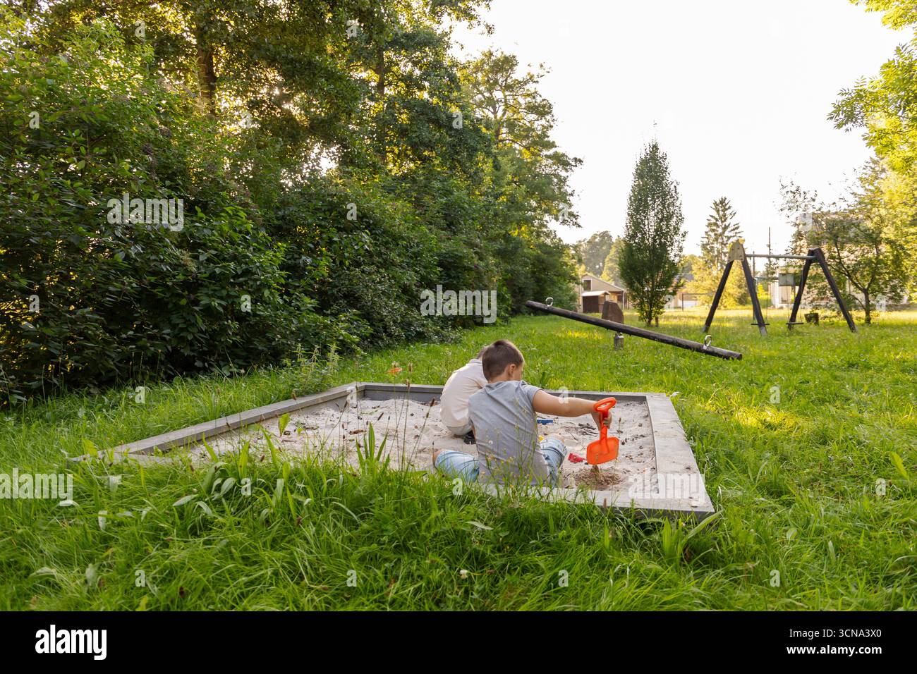 Two children are happily playing in a sandbox filled with sand, using ...