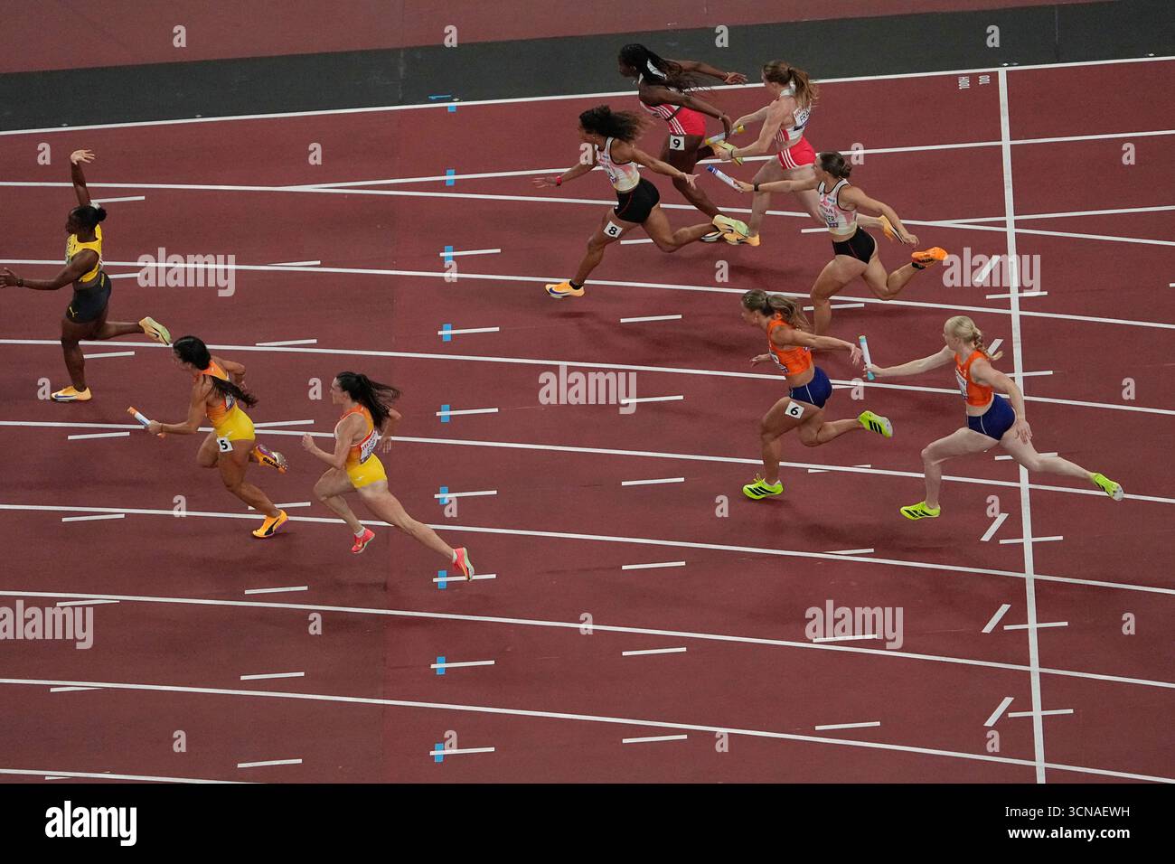 Athletes exchange the baton during a women's 4 X 100 meters relay heat ...