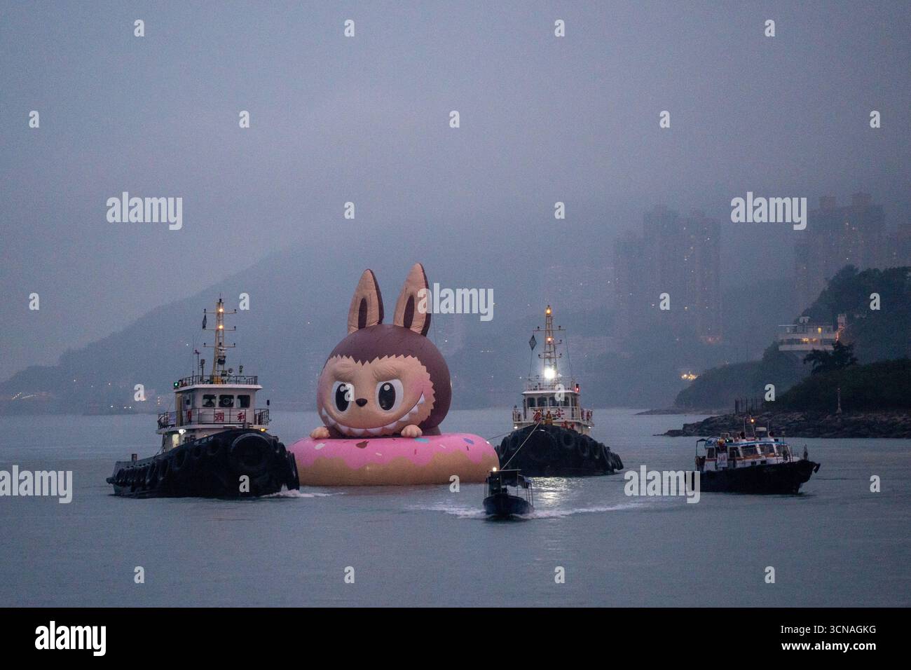 A large inflatable Labubu Sculpture being pulled by a tug boat on ...