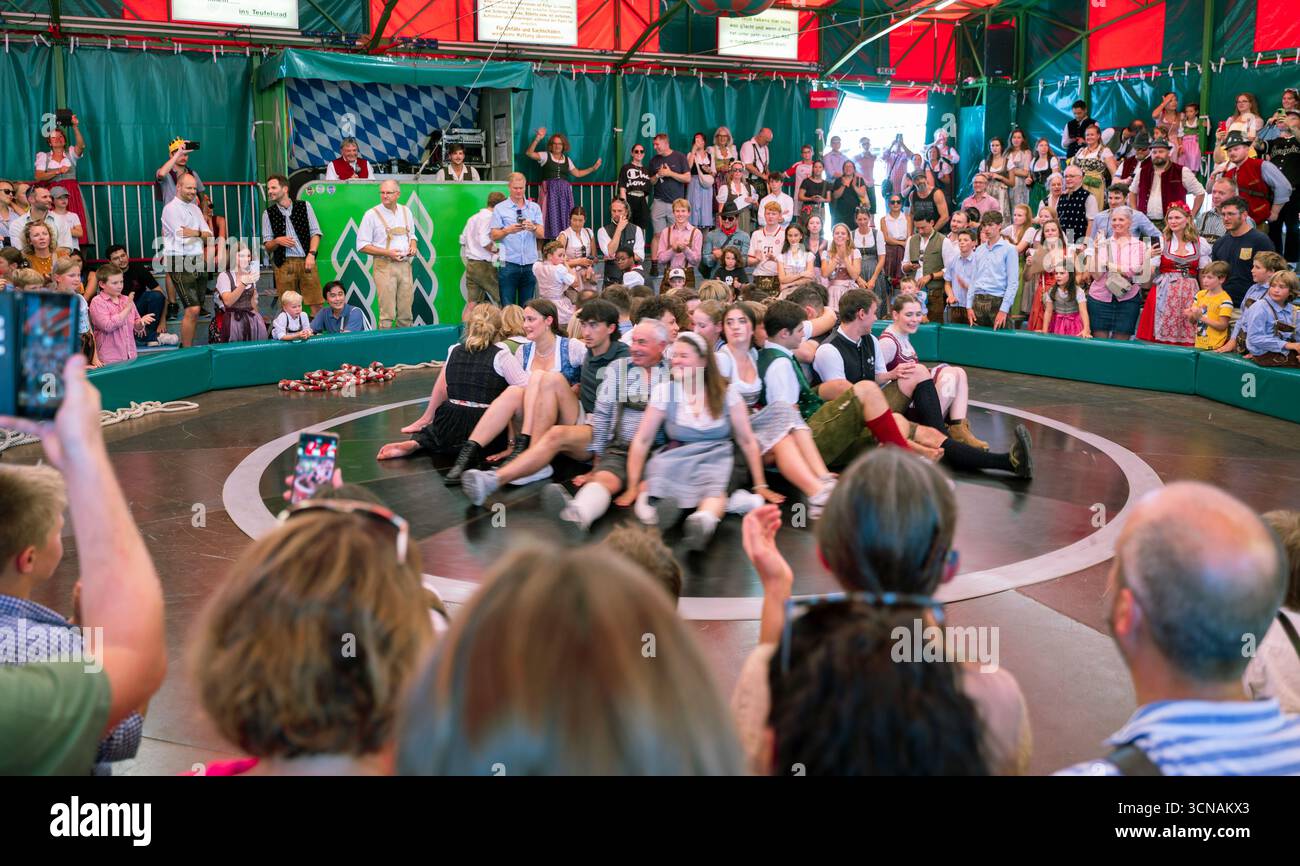 20 September 2025, Bavaria, Munich: Visitors sit on the Devil's Wheel ...