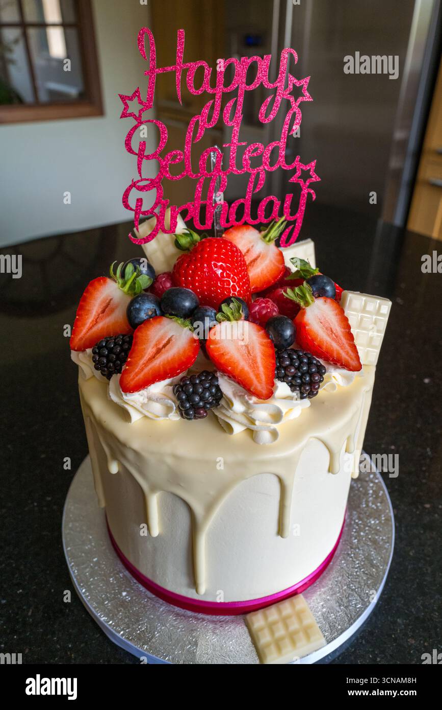 A well presented belated birthday cake with a mixed fruit selection ...