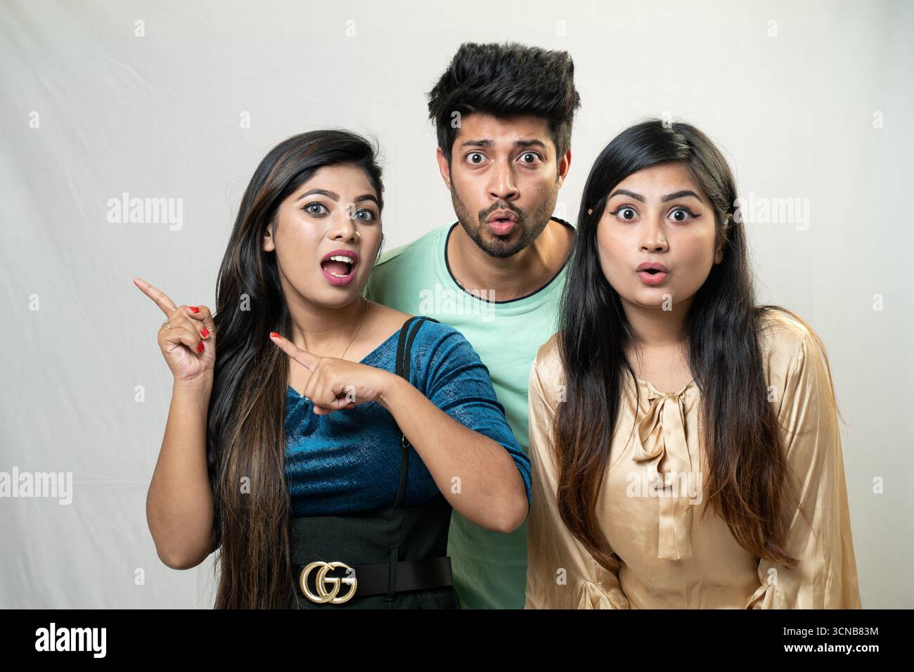 Three shocked friends pointing and looking Stock Photo - Alamy