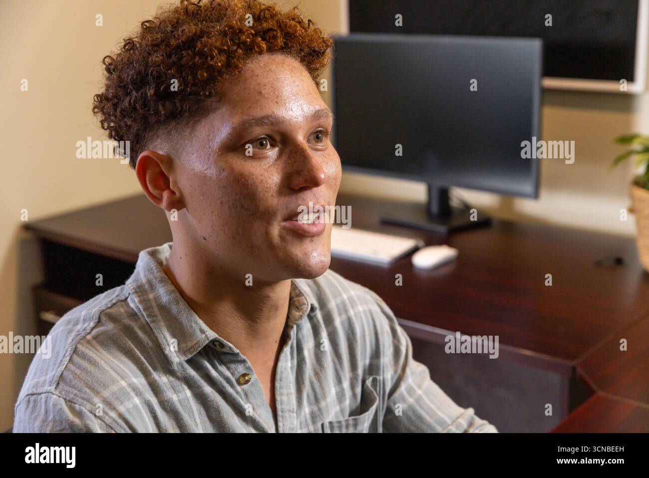 Male office worker speaking while sitting at office desk with computer ...