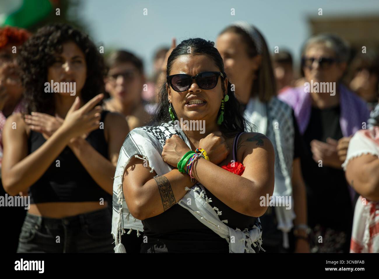 A woman makes protest signs with her hands clasped at a demonstration ...