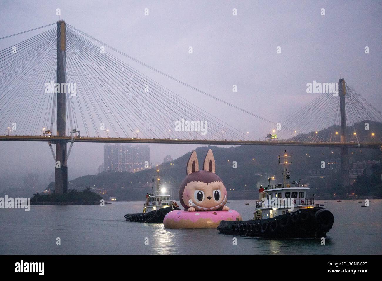 A large inflatable Labubu Sculpture being pulled by a tug boat on ...