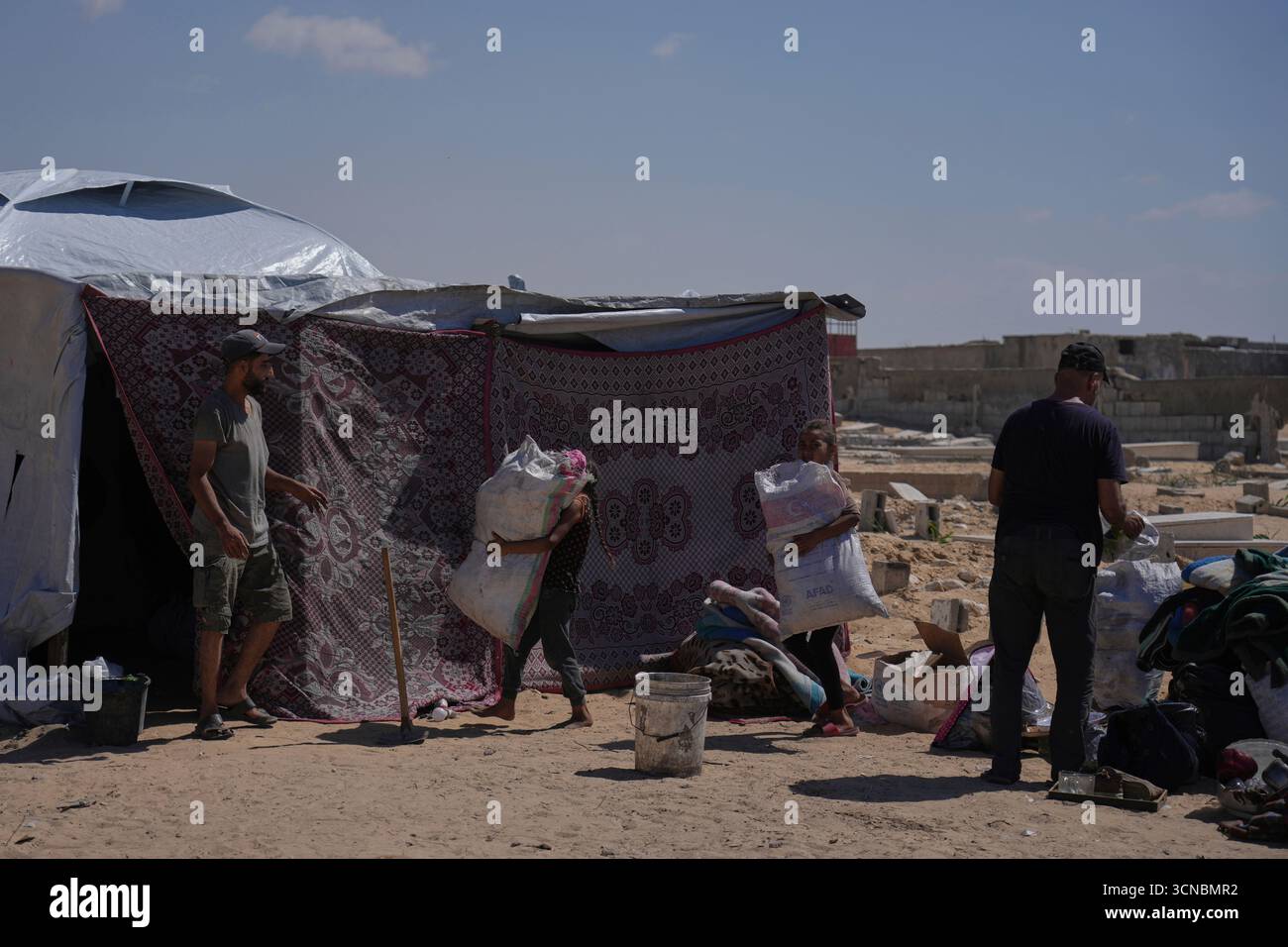 Al-Dali family move their belongings into a tent set up in a cemetery ...