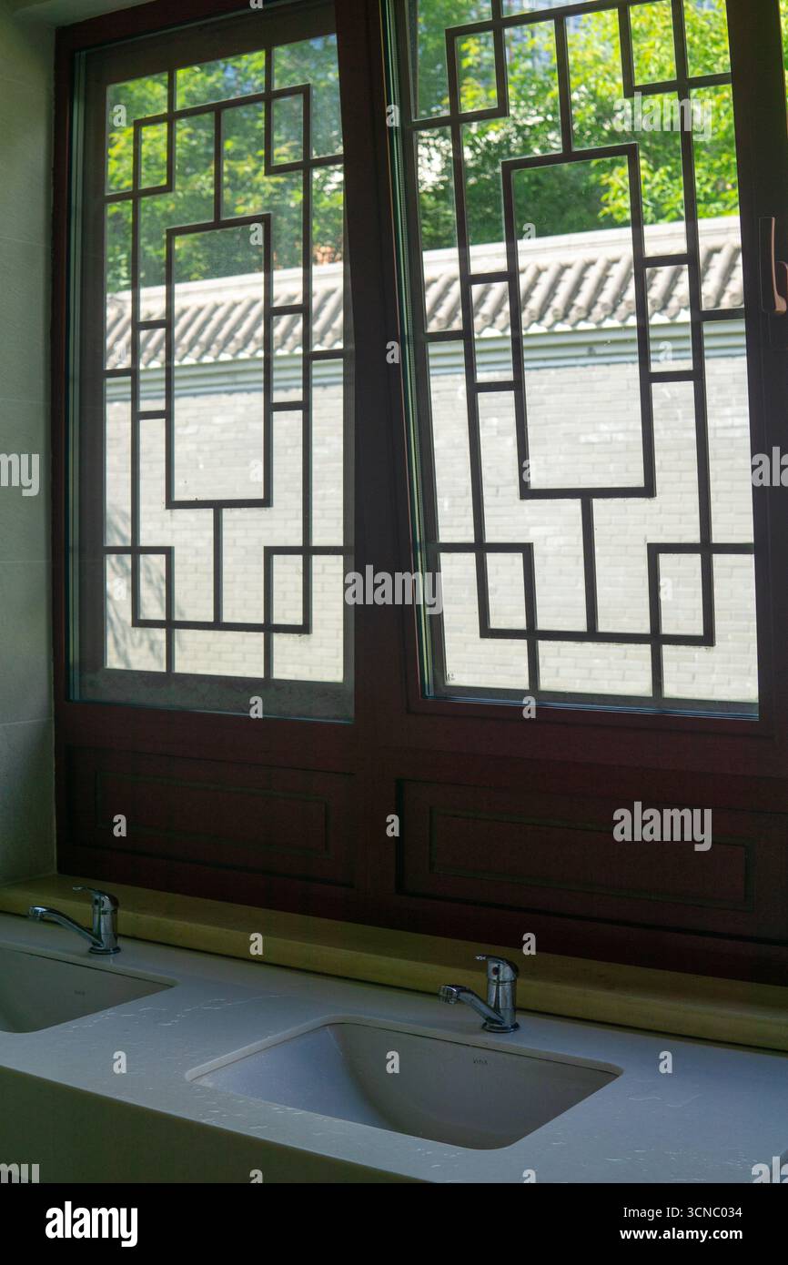 Sinks in a public restroom with an oriental style window in the ...