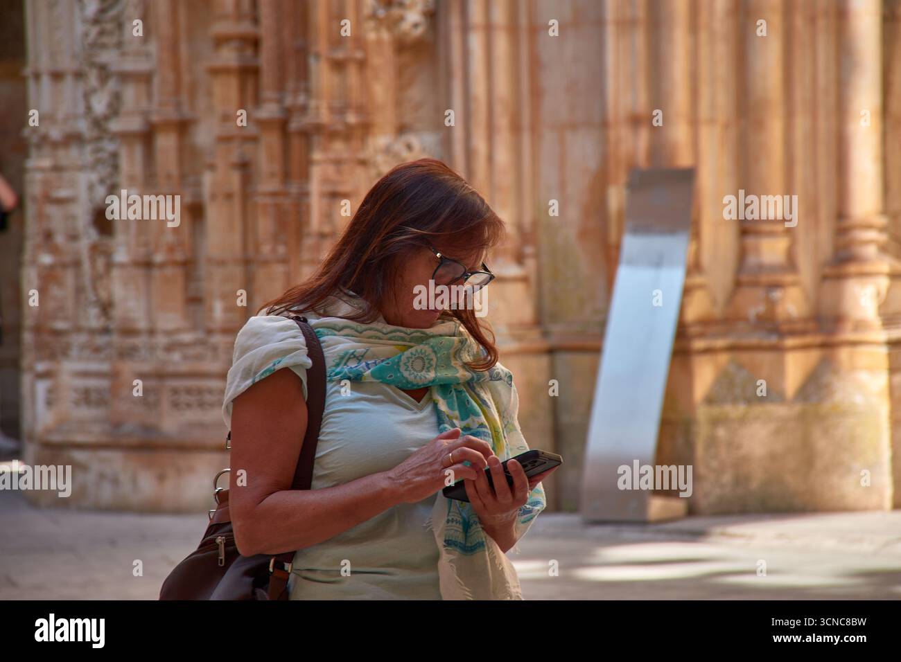 A mature woman wearing glasses and a patterned scarf appears focused ...
