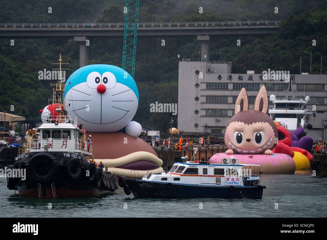 A large inflatable Doraemon Sculpture being pulled by a tug boat on ...