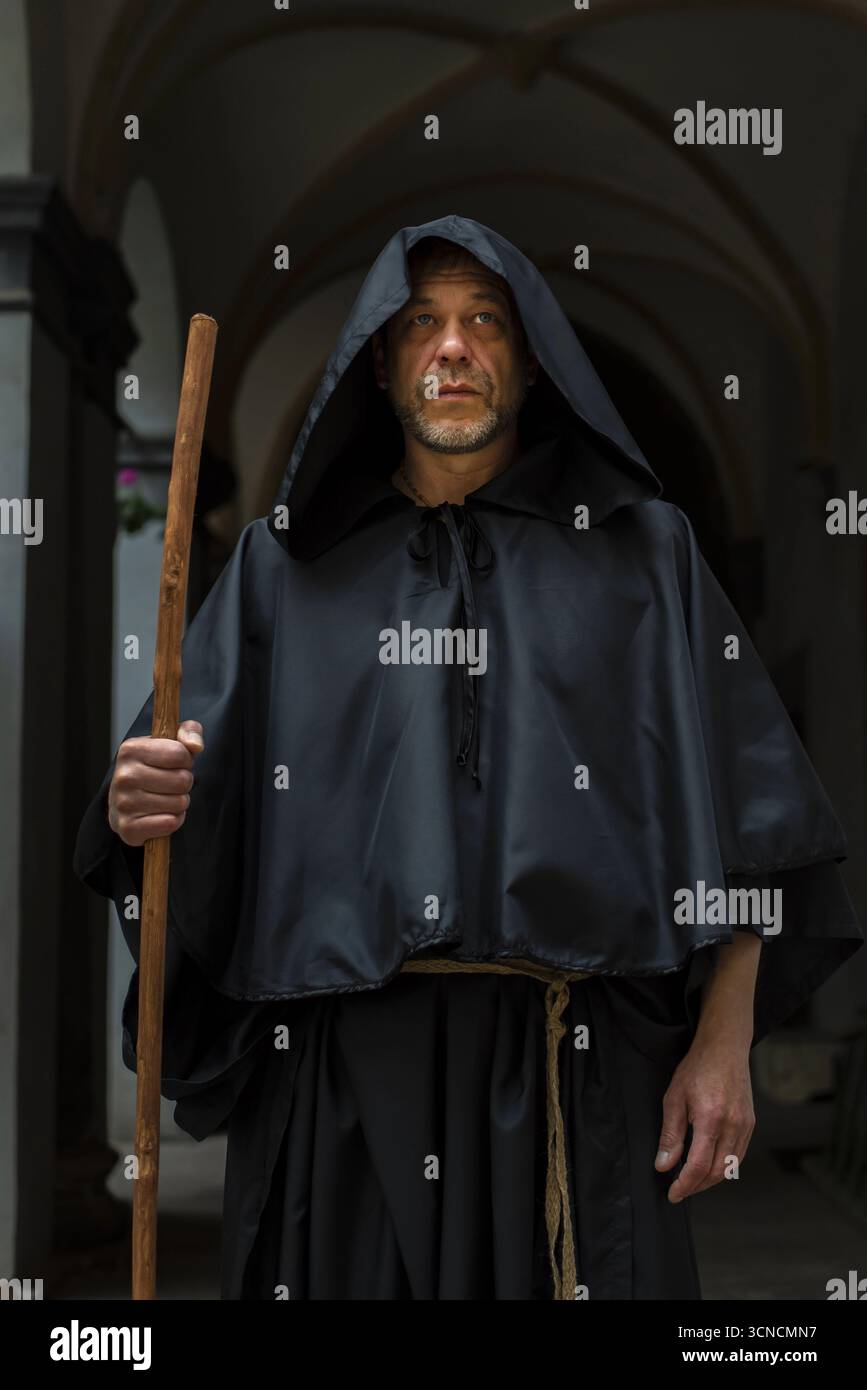 Medieval monk in black hooded cloak holding a staff Stock Photo - Alamy
