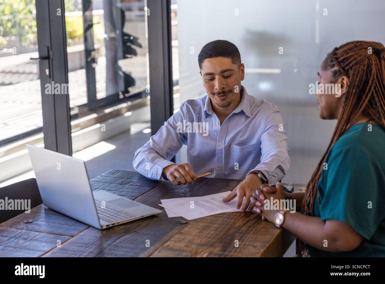 Diverse advisor and client discussing documents, laptop at office table ...
