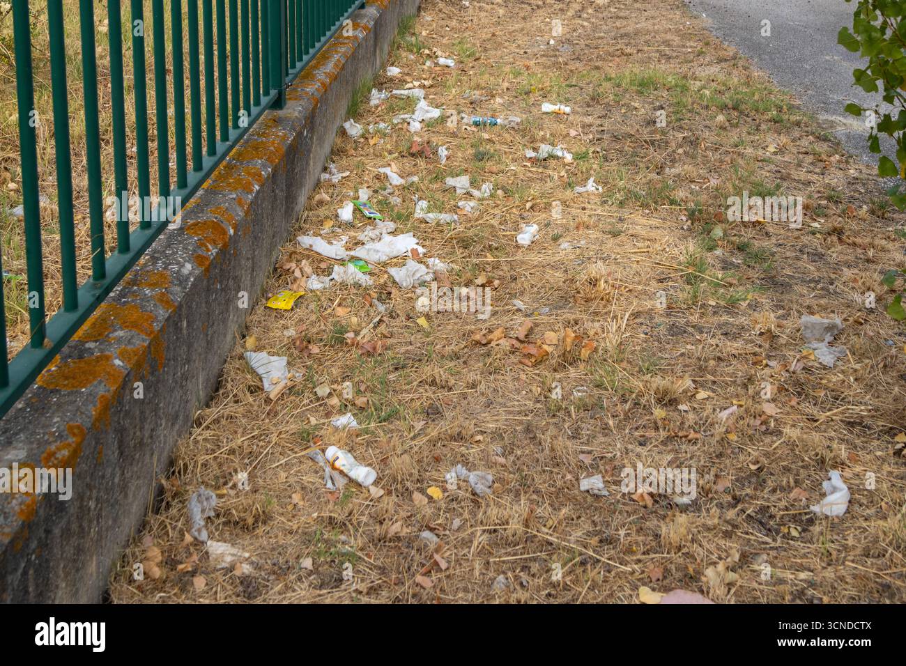 Waste polluting the ground near a green fence, highlighting ...
