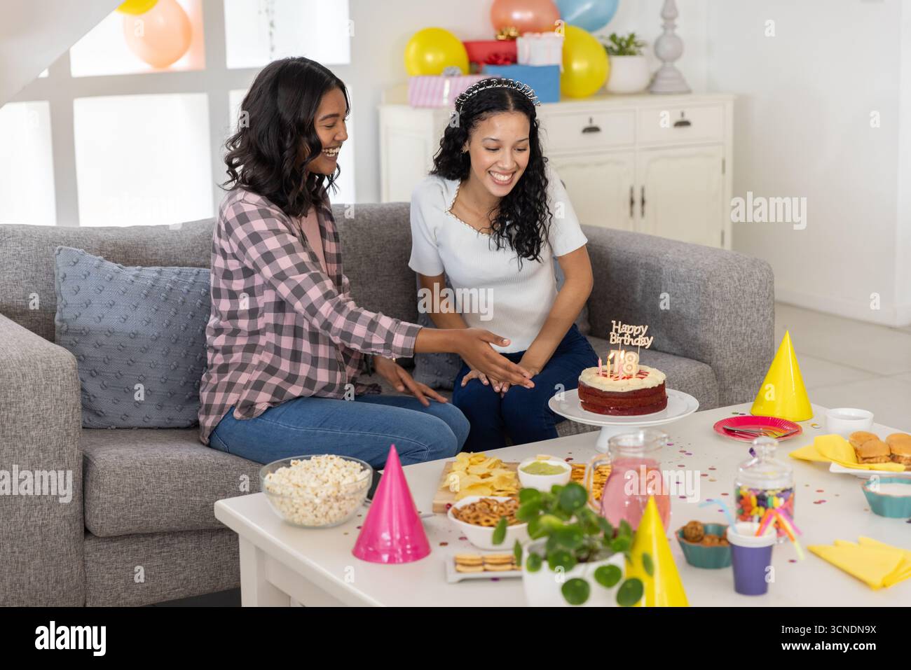 Diverse mom and teenage daughter sitting on couch at home celebrating ...
