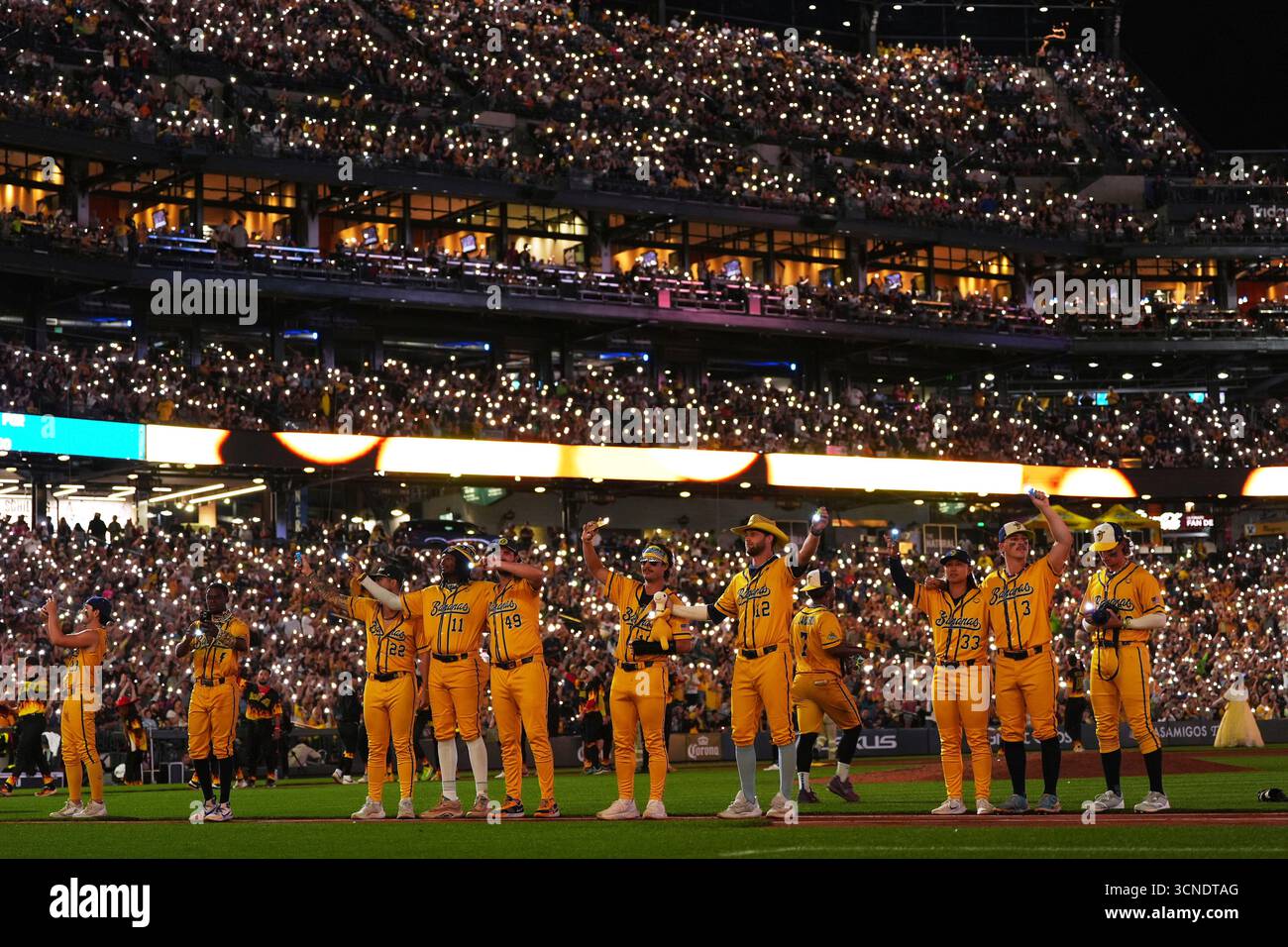Savannah Bananas players hold up flashlights as fans turn on their ...