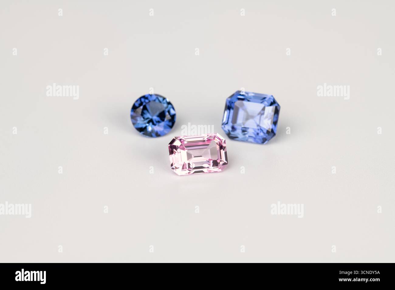 Three different colored gems are displayed on a white background. The ...