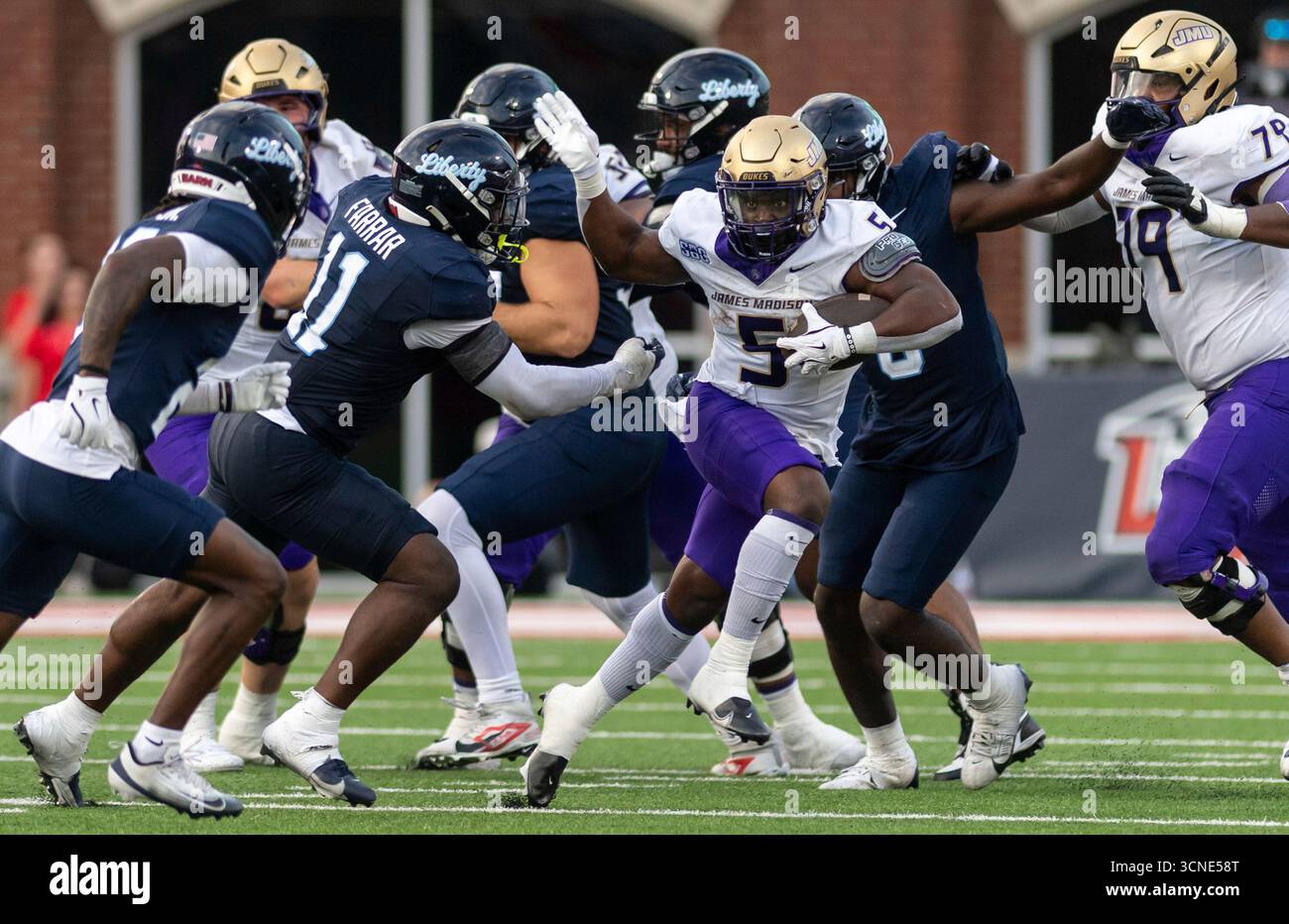 James Madison running back Ayo Adeyi (5) runs through a gap in the ...