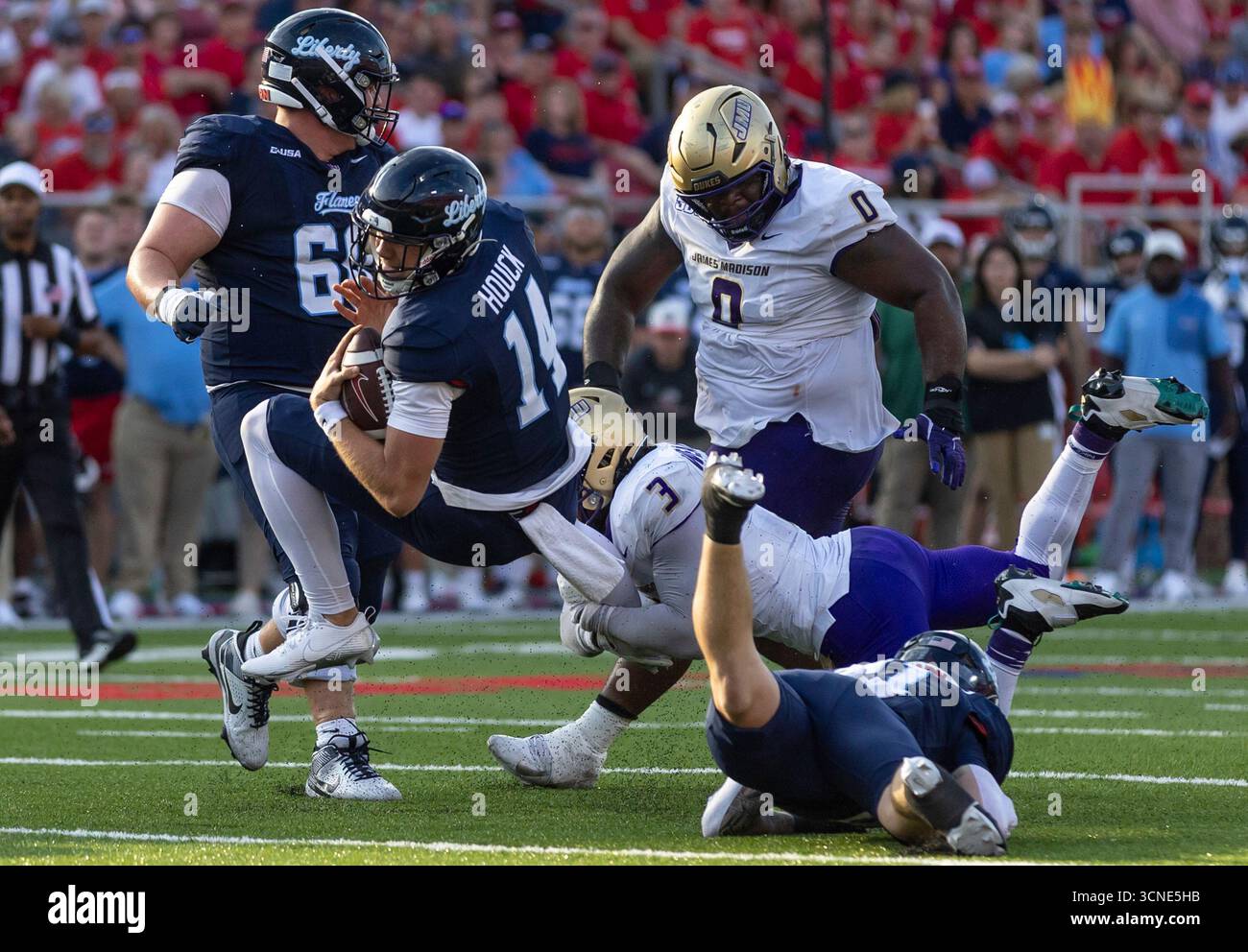 Liberty quarterback Ethan Houck (14) gets wrapped up by James Madison ...