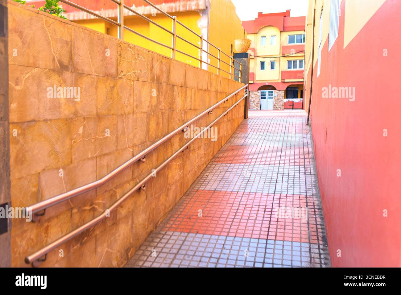 Accessible ramp with handrails and a vibrant tiled path leading to ...
