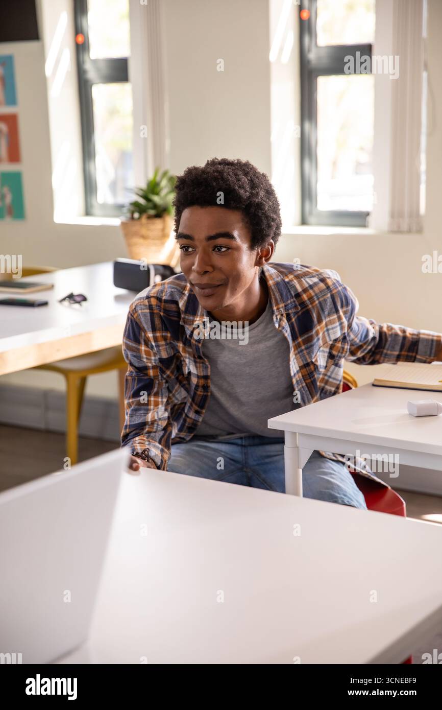 African american student leaning and reaching for pen Stock Photo - Alamy