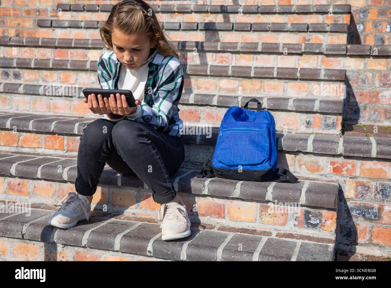 Girl student sitting on outdoor brick steps using touchscreen device ...