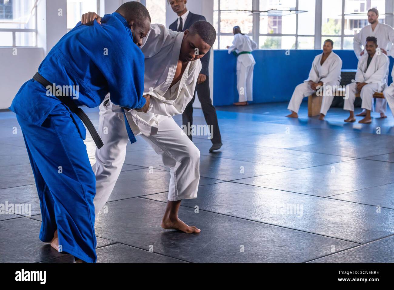 African American male martial artists grappling on matted floor under ...