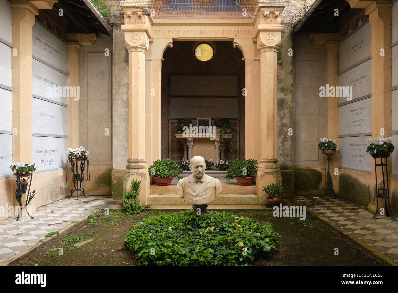 Quiet mausoleum courtyard with bust sculpture. At the Orario Cimitero ...