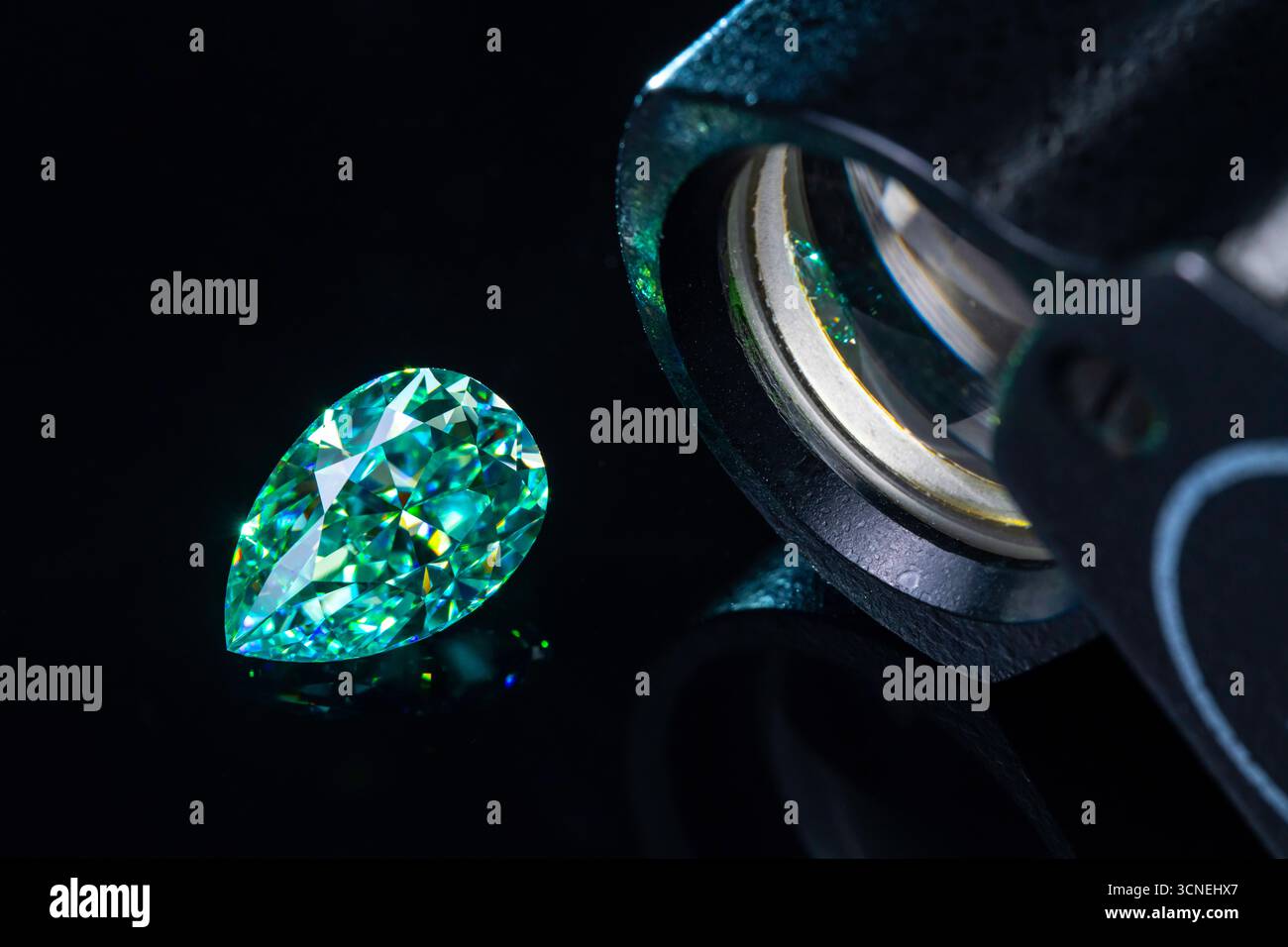 A green gemstone is on a table next to a magnifying glass. The gemstone ...