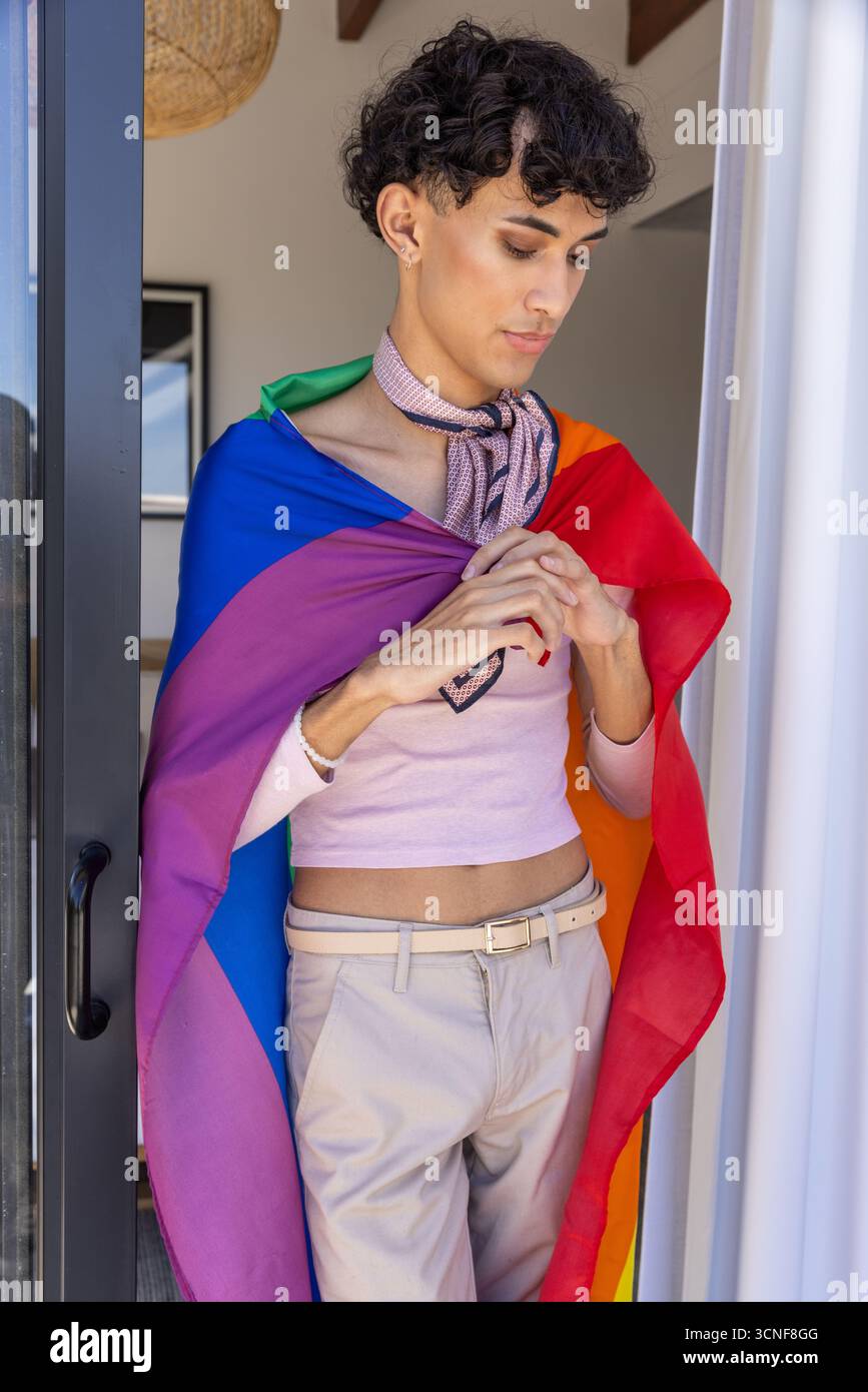 Man in twenties standing in home doorway draping pride flag on ...