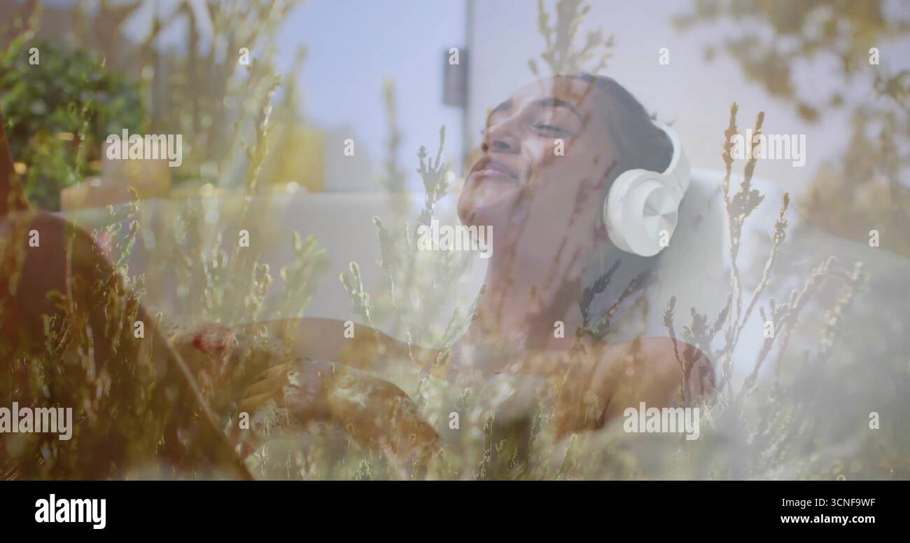 Reclining woman wearing white top soaking in music on living room sofa ...