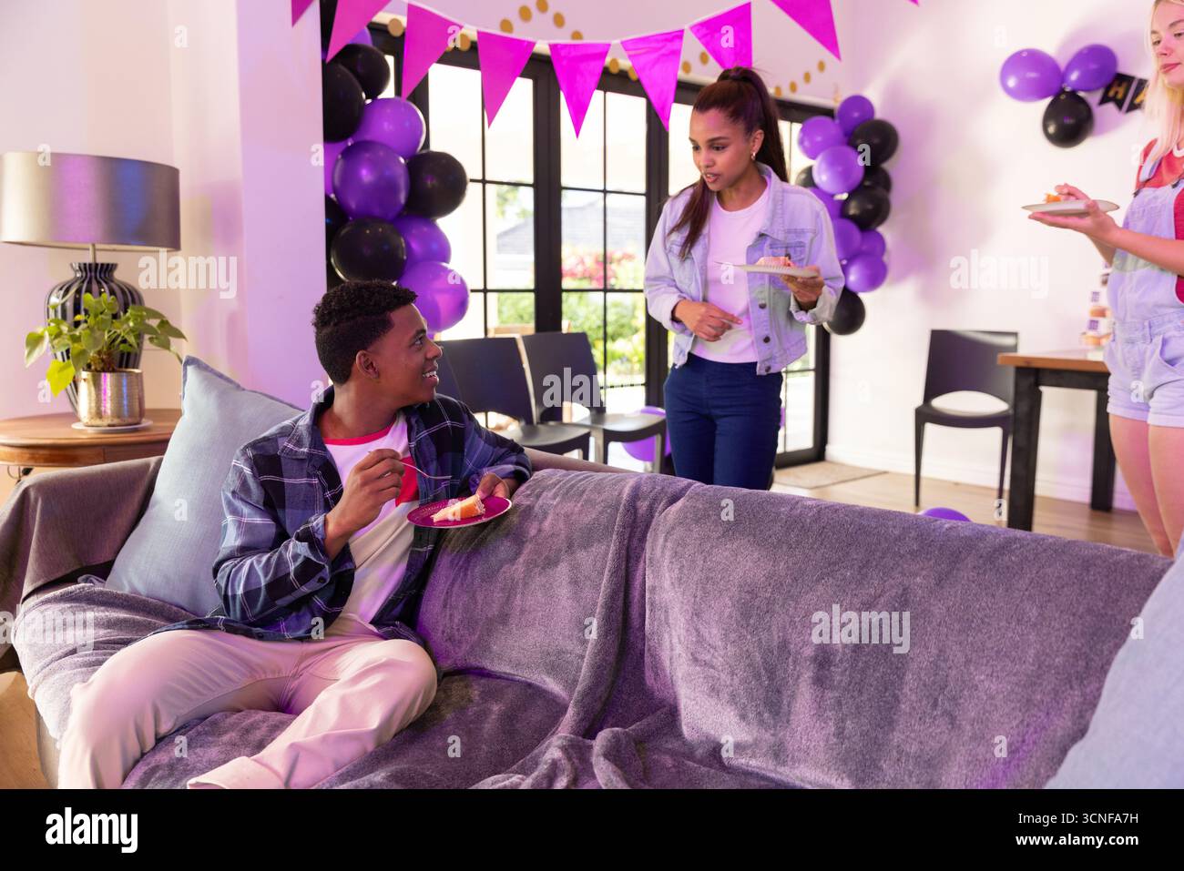 Diverse teenage friends gathering at home with balloons and bunting ...