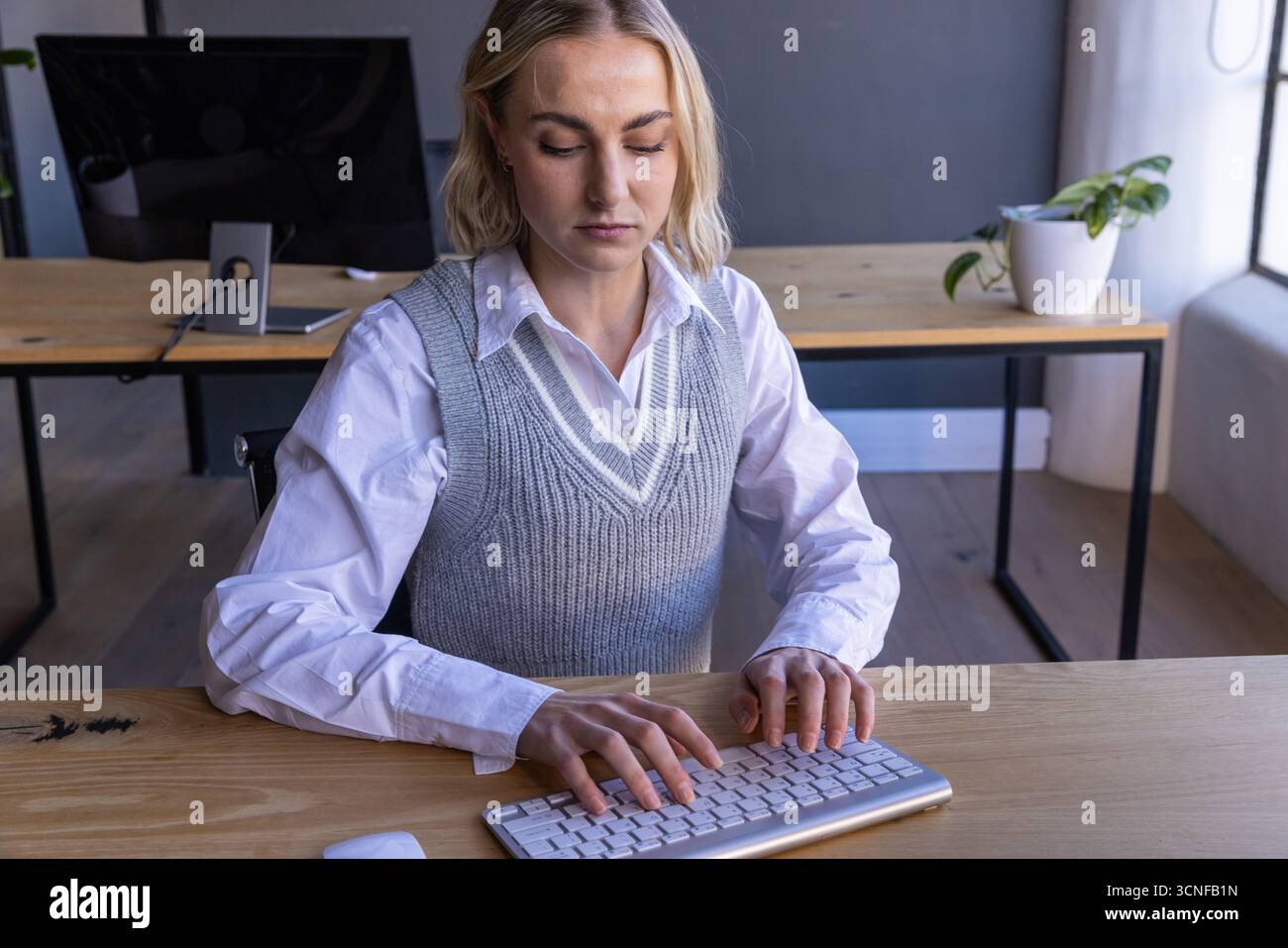Female office worker typing on wireless keyboard at office desk with ...