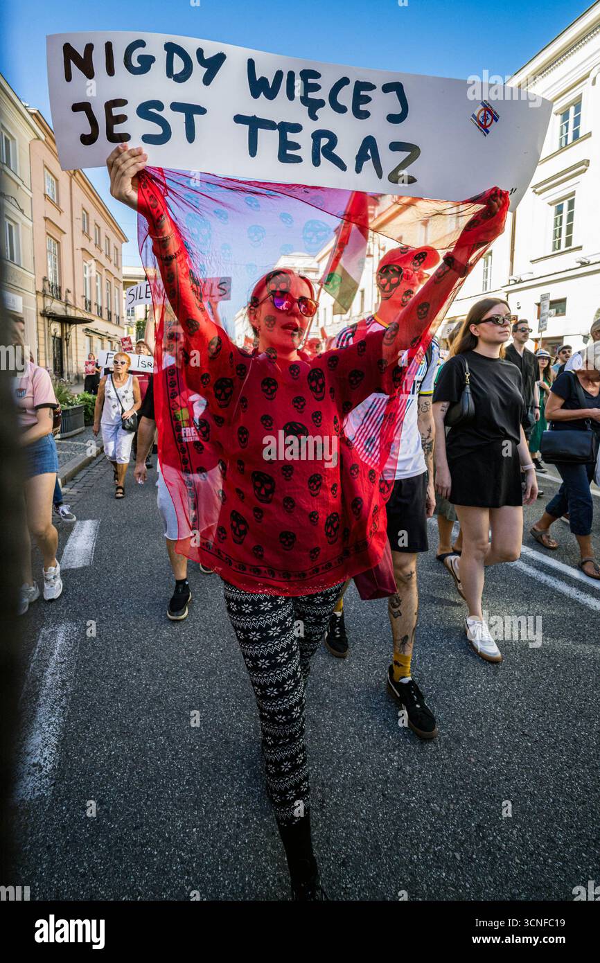 A protester holds a placard that says, in Polish, "Never again is now ...